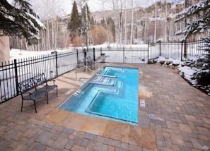 Uma piscina retangular cercada por uma vedação de metal preto.