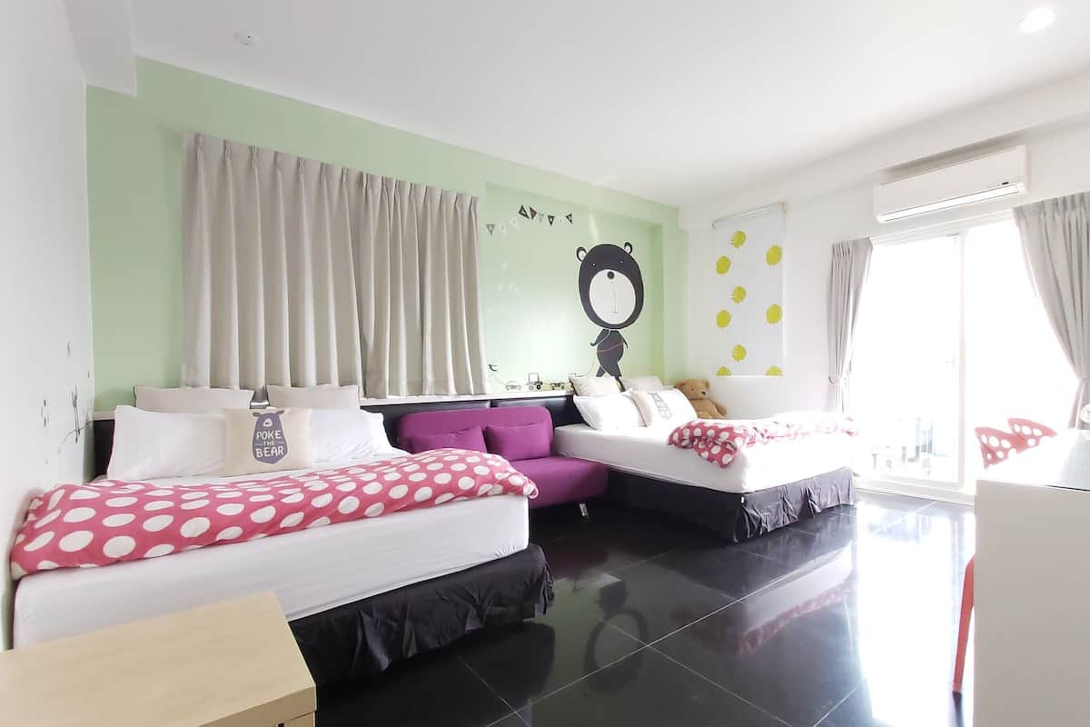 Quarto de hotel com duas camas, um sofá, um espelho e uma janela com cortinas.