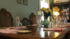 Mesa posta com pratos, talheres e um vaso de flores amarelas.