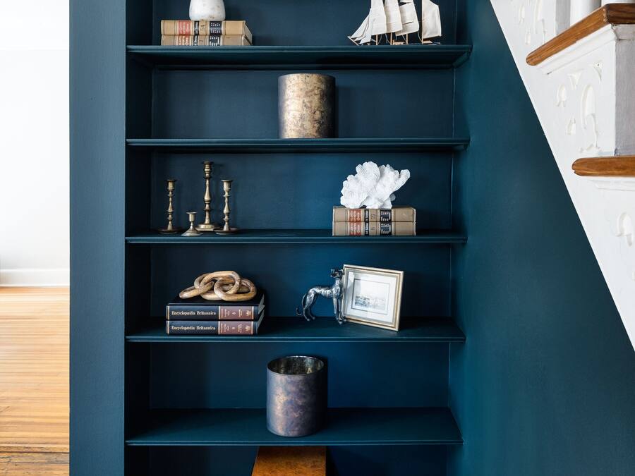Uma estante azul escura com objetos decorativos e livros.