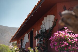 Um edifício com fachada vermelha, persianas brancas e telhado em telhas.