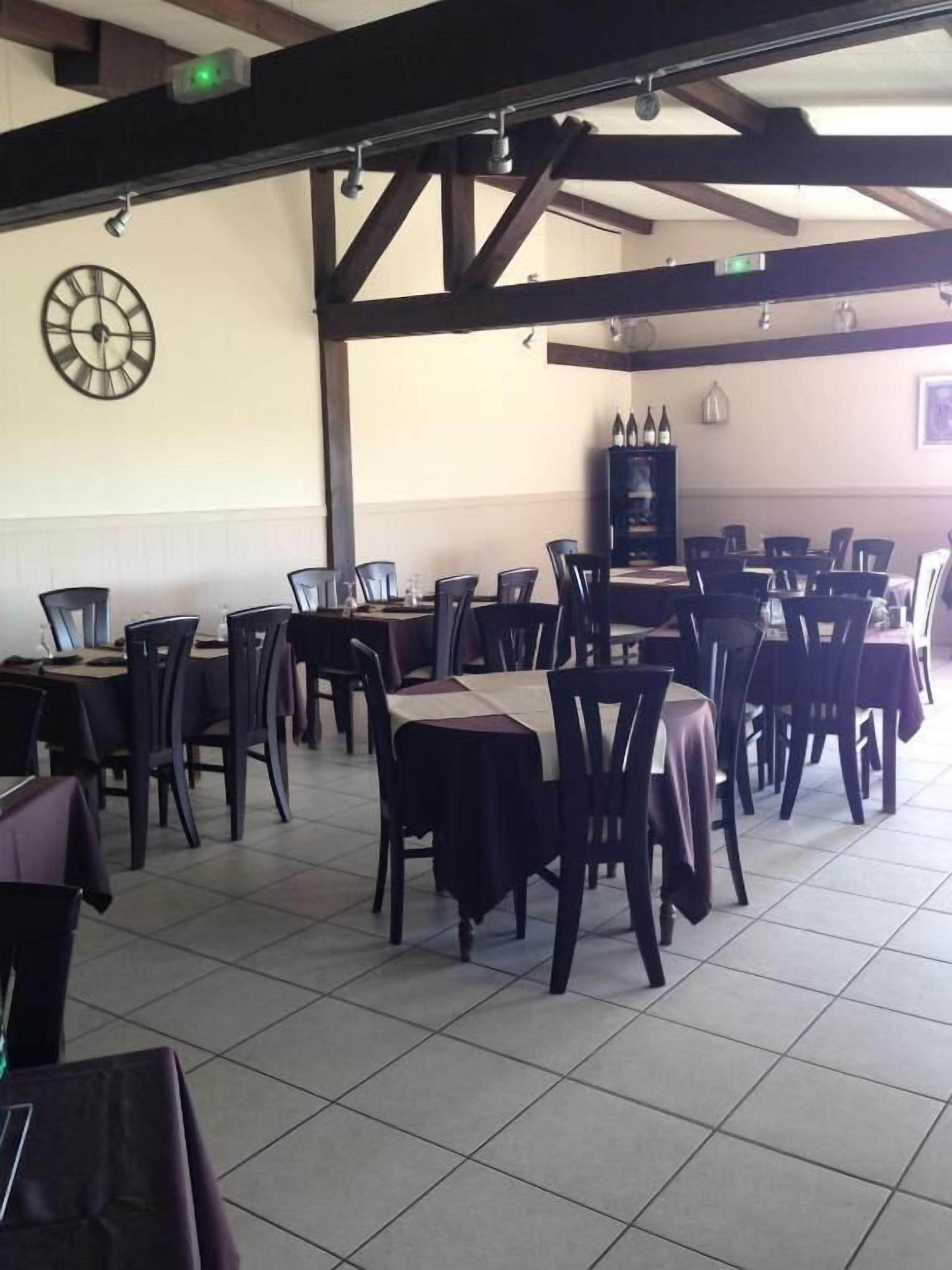 Um restaurante com várias mesas e cadeiras, um relógio na parede e piso de azulejos.