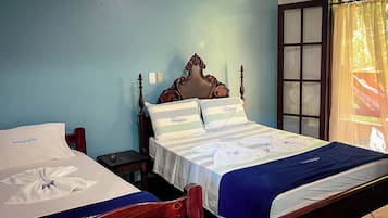 Uma cama de casal com cabeceira de madeira, mesa de cabeceira e janela com cortina.