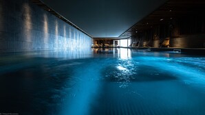Piscina interior ampla, com design alongado e teto alto.