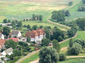 Uma vila rural com casas tradicionais, estradas sinuosas e vegetação ao redor.