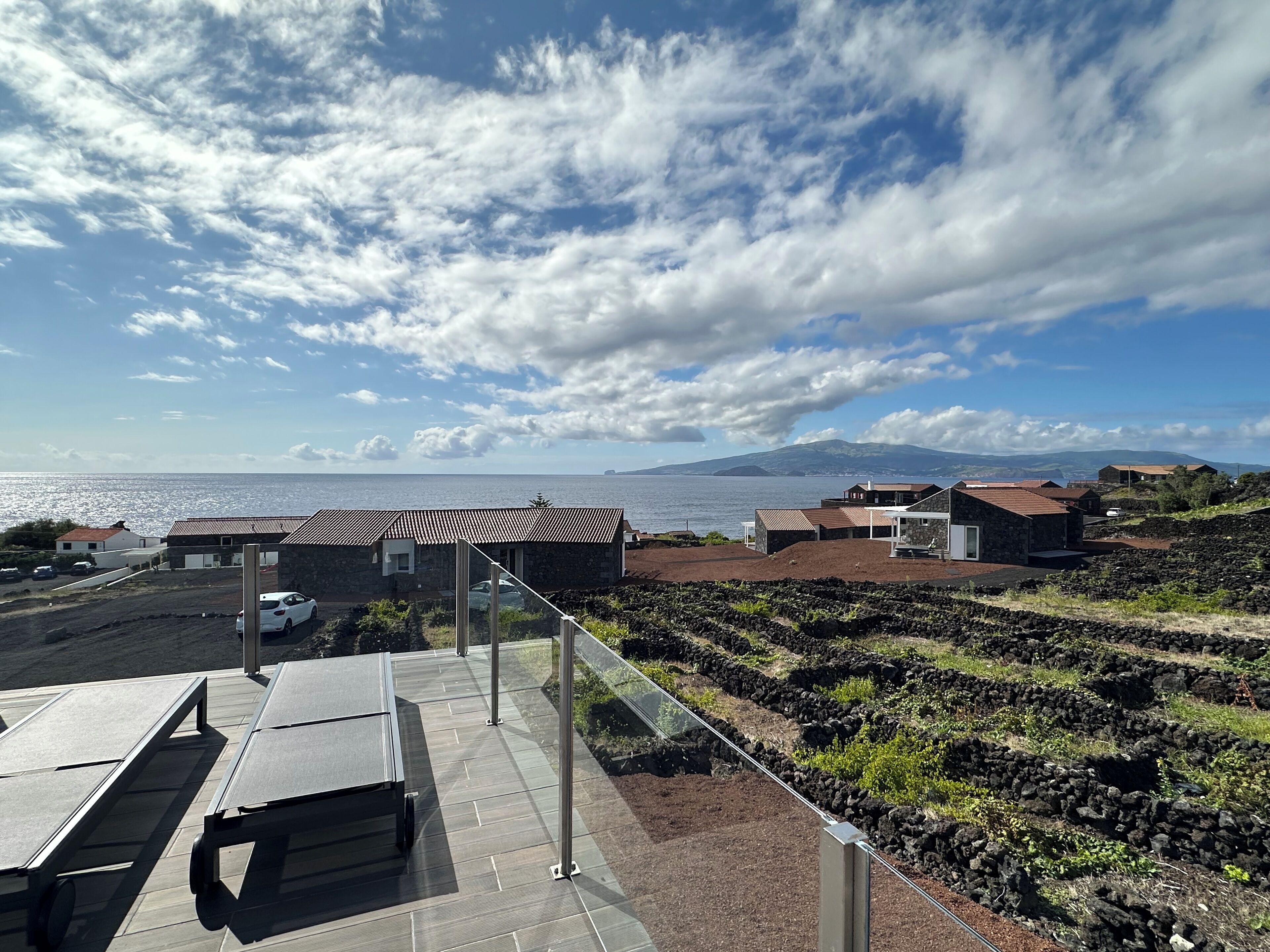 Um imóvel costeiro com terraço, edifícios de pedra e vista para o mar e montanhas.
