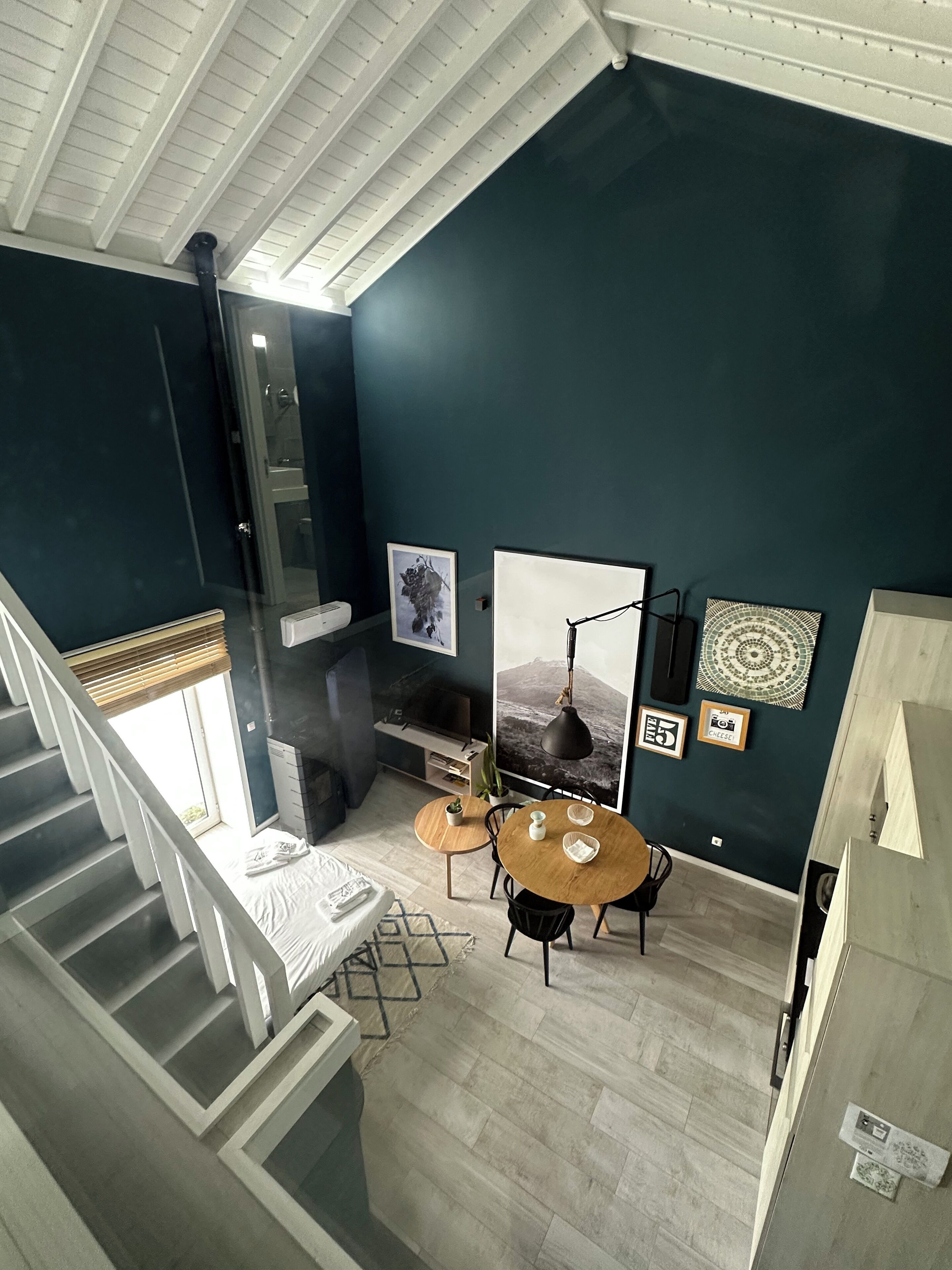 Um espaço de estar moderno com escada, área de jantar com mesa redonda e uma grande janela que oferece luz natural.