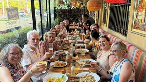 Um grupo de pessoas jantando em um restaurante, com uma mesa repleta de pratos e bebidas.