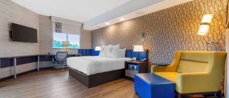Quarto de hotel moderno com uma cama grande, uma escrivaninha, uma cadeira e uma televisão.