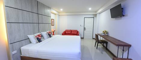 Quarto moderno com cama grande, escrivaninha e televisão.