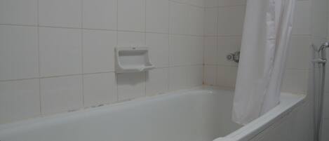 Um banheiro com banheira, chuveiro e um dispensador de sabonete líquido na parede.