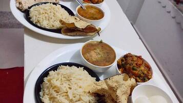 Uma mesa com vários pratos, incluindo arroz, pães achatados e diversos curries.
