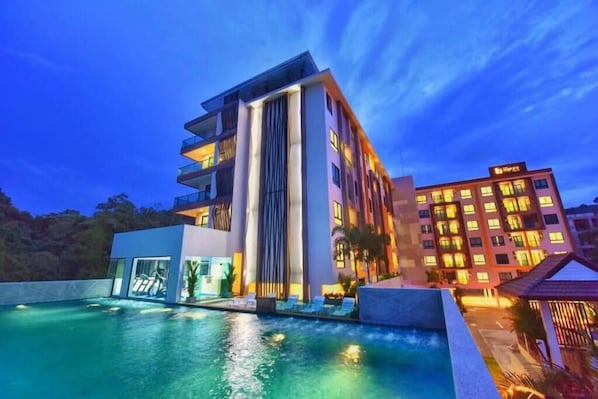 Um hotel moderno com piscina, várias varandas e fachada bem iluminada.
