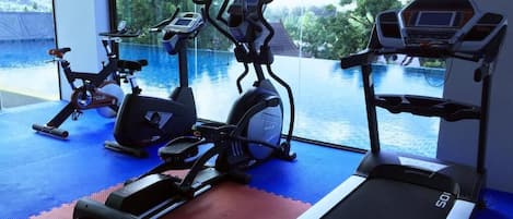 Uma academia com esteiras, bicicletas ergométricas e um remo.