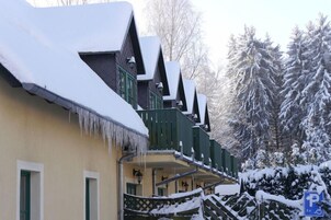 Um edifício coberto de neve com telhado inclinado e corrimãos verdes.