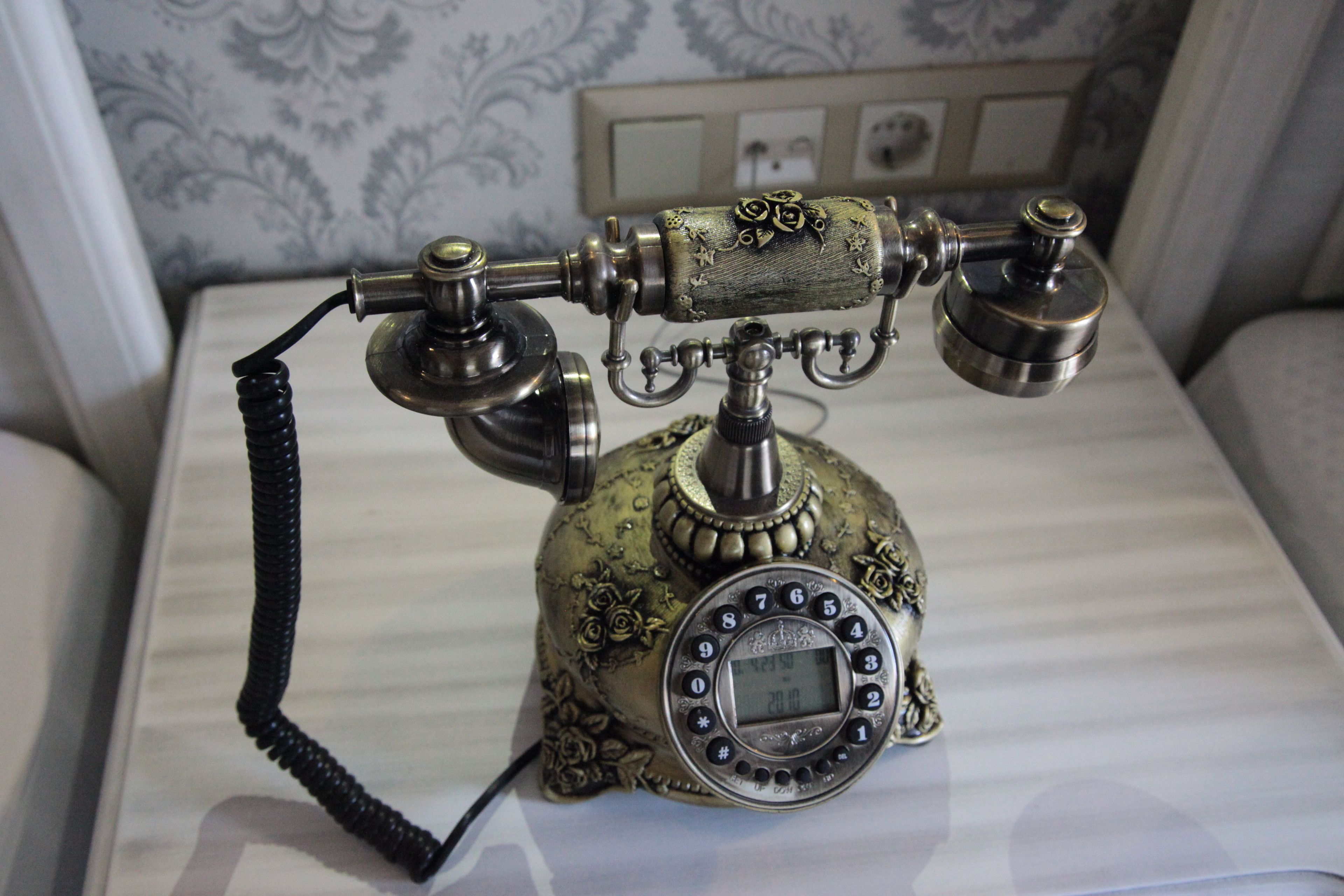 Um telefone antigo com discagem rotativa sobre uma mesa.