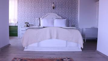 Quarto com uma cama grande, cômoda e mesa de cabeceira.