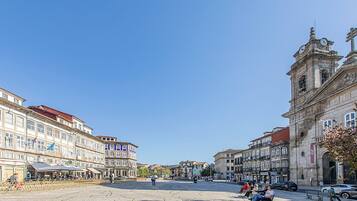 Uma praça histórica com calçamento de pedras, arquitetura clássica e uma torre do relógio imponente.