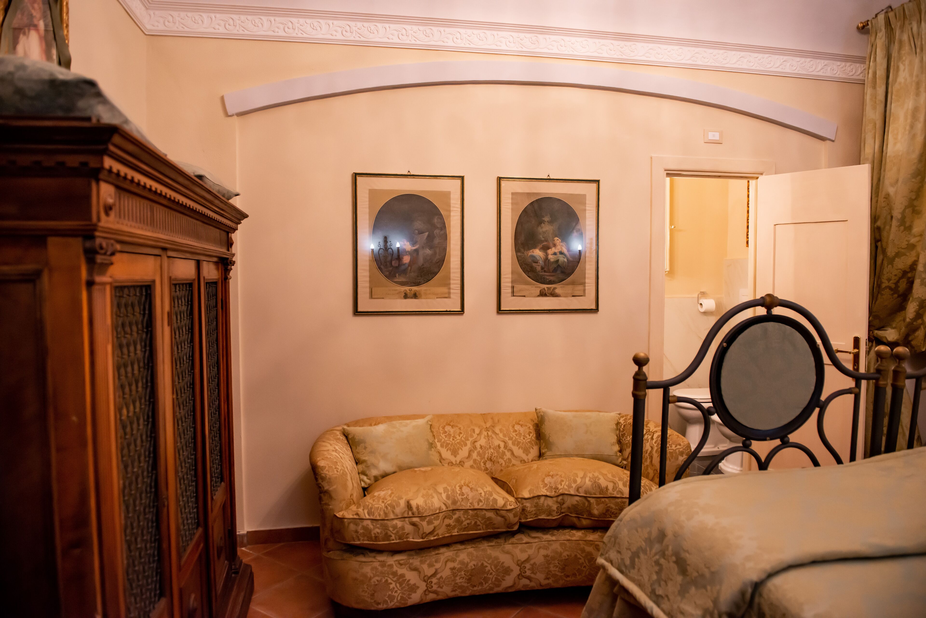 Um quarto com sofá, cama, um armário de madeira e duas imagens emolduradas na parede.