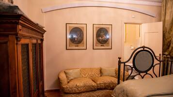 Um quarto com sofá, cama, um armário de madeira e duas imagens emolduradas na parede.