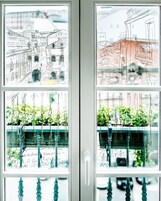 Uma janela com vista para um edifício e vegetação.