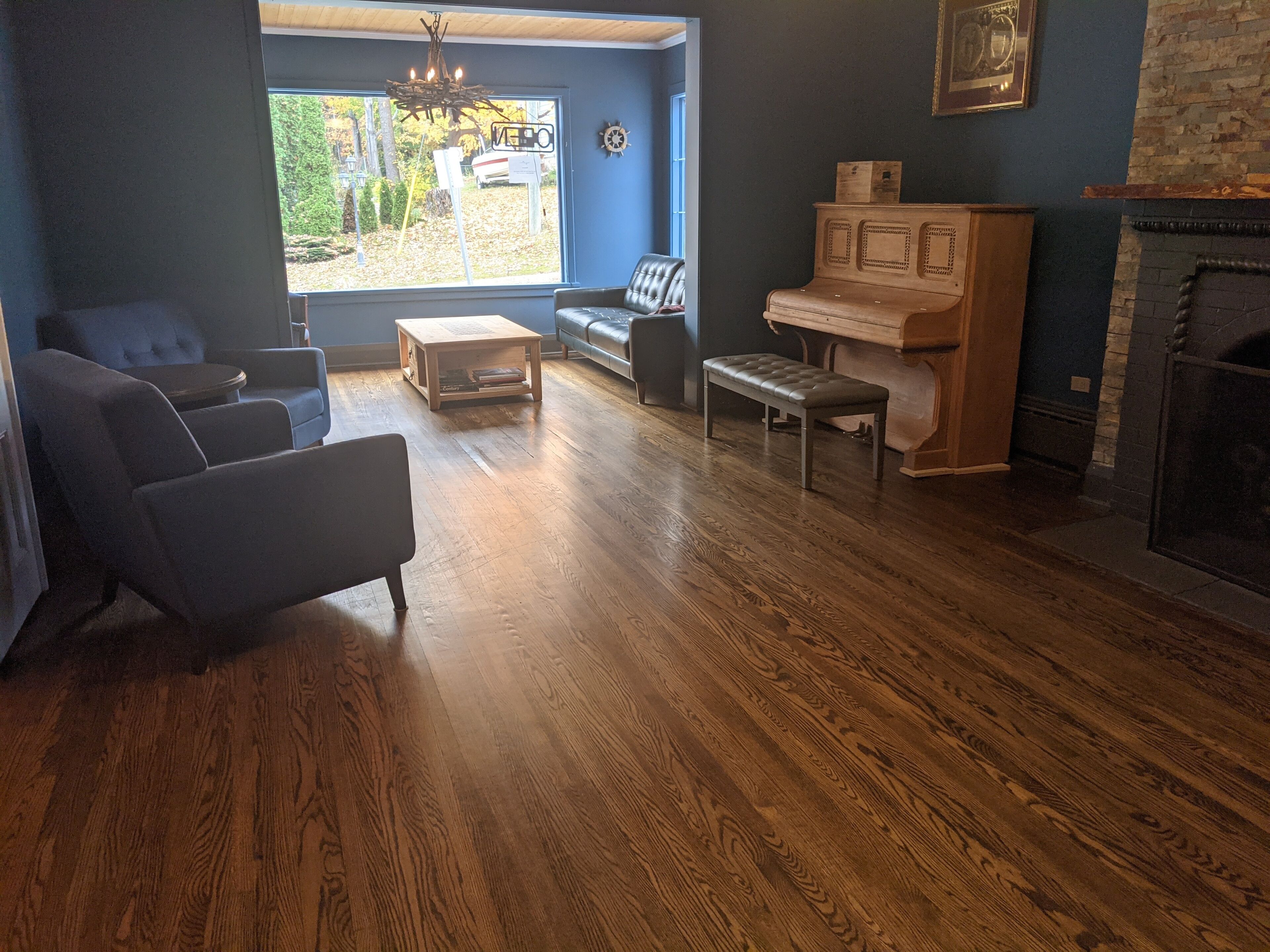 Uma sala de estar com um piano, um sofá, um banco e uma mesa de centro.