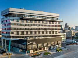 Um hotel de vários andares com design moderno, exibindo uma placa grande com a palavra 'HOTEL' na fachada.