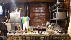 Uma área de bar com balcão de pedra, banquetes e variedade de garrafas.