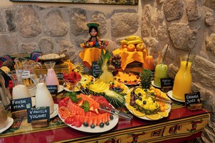 Mesa de buffet com diversas opções de comida, incluindo frutas, legumes e bebidas, com etiquetas identificando o tipo de alimento e bebida.