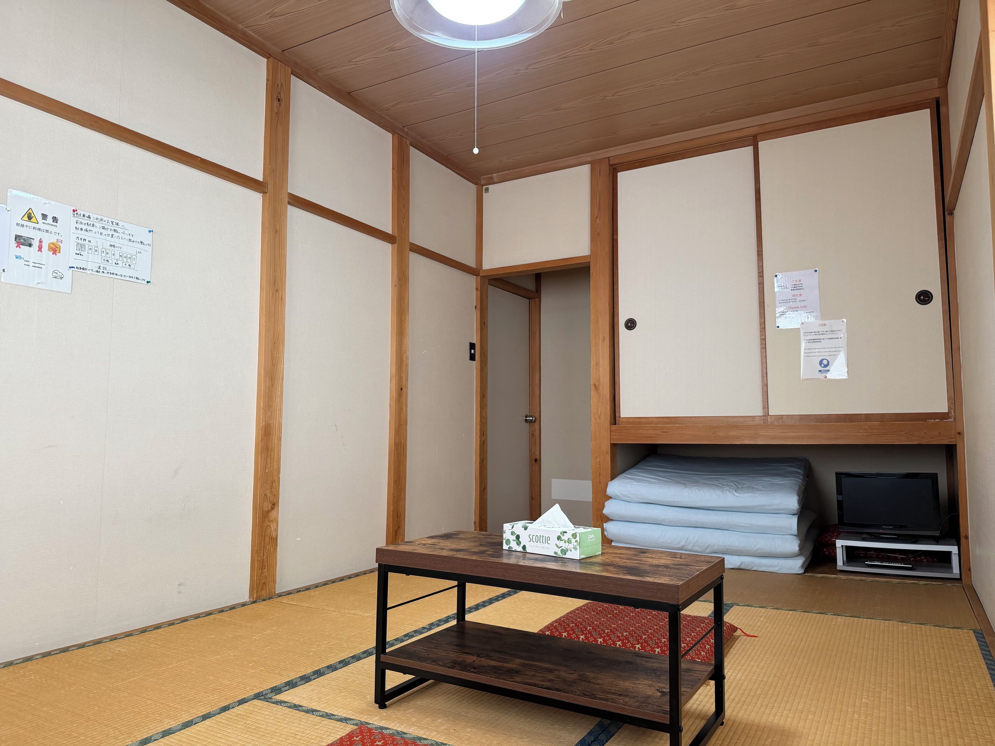 Quarto japonês tradicional com tatames, uma mesa de madeira baixa e uma televisão.