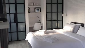 Um quarto moderno com uma cama grande, uma cadeira branca e uma escrivaninha.