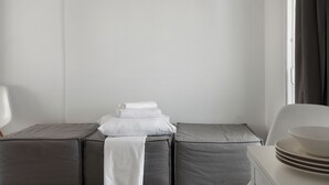 Quarto minimalista com uma cama, mesa de cabeceira com uma tigela e janela com cortinas.