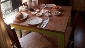 Mesa de jantar posta com pratos, copos e uma baguete.