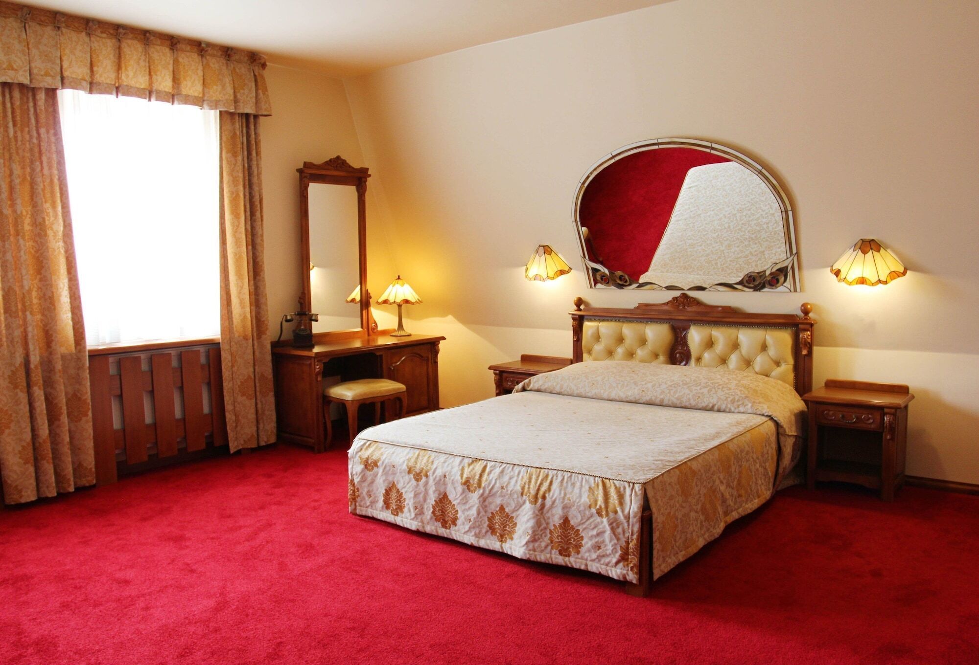 Quarto de hotel com uma cama grande, penteadeira, espelho e duas luminárias de cabeceira.