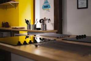 Uma bancada de cozinha com utensílios, uma chaleira e um cartaz na parede.