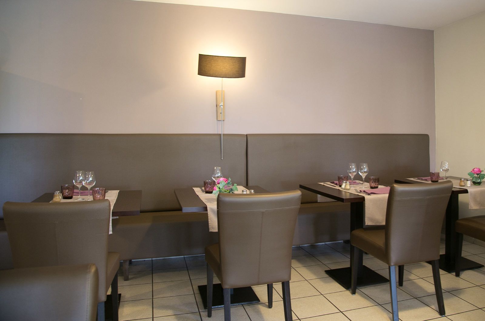Um restaurante com assentos em cabines, uma mesa central e um candeeiro fixo na parede.