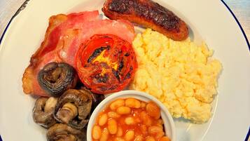 Prato com diversas opções de café da manhã, incluindo salsichas, bacon, ovos, cogumelos e feijão.