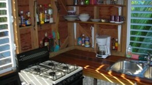 Cozinha com fogão a gás, cafeteira e prateleiras com diversos objetos.