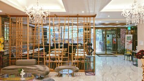 Um hall de hotel com design moderno, apresentando um painel de madeira, áreas de estar confortáveis e lustres.