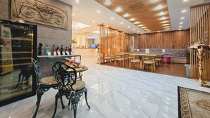 Um saguão de hotel com design moderno, apresentando uma recepção, área de estar e elementos decorativos.
