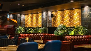 Um restaurante com assentos de couro, mesas e parede estampada.