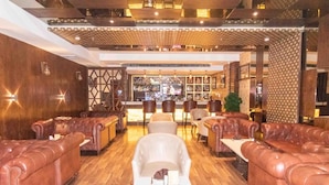 Um hall com sofás de couro, espaço de bar e balcão de recepção.