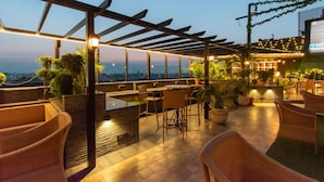 Terraço no telhado com área de estar ao ar livre, piscina e vista para a paisagem urbana.