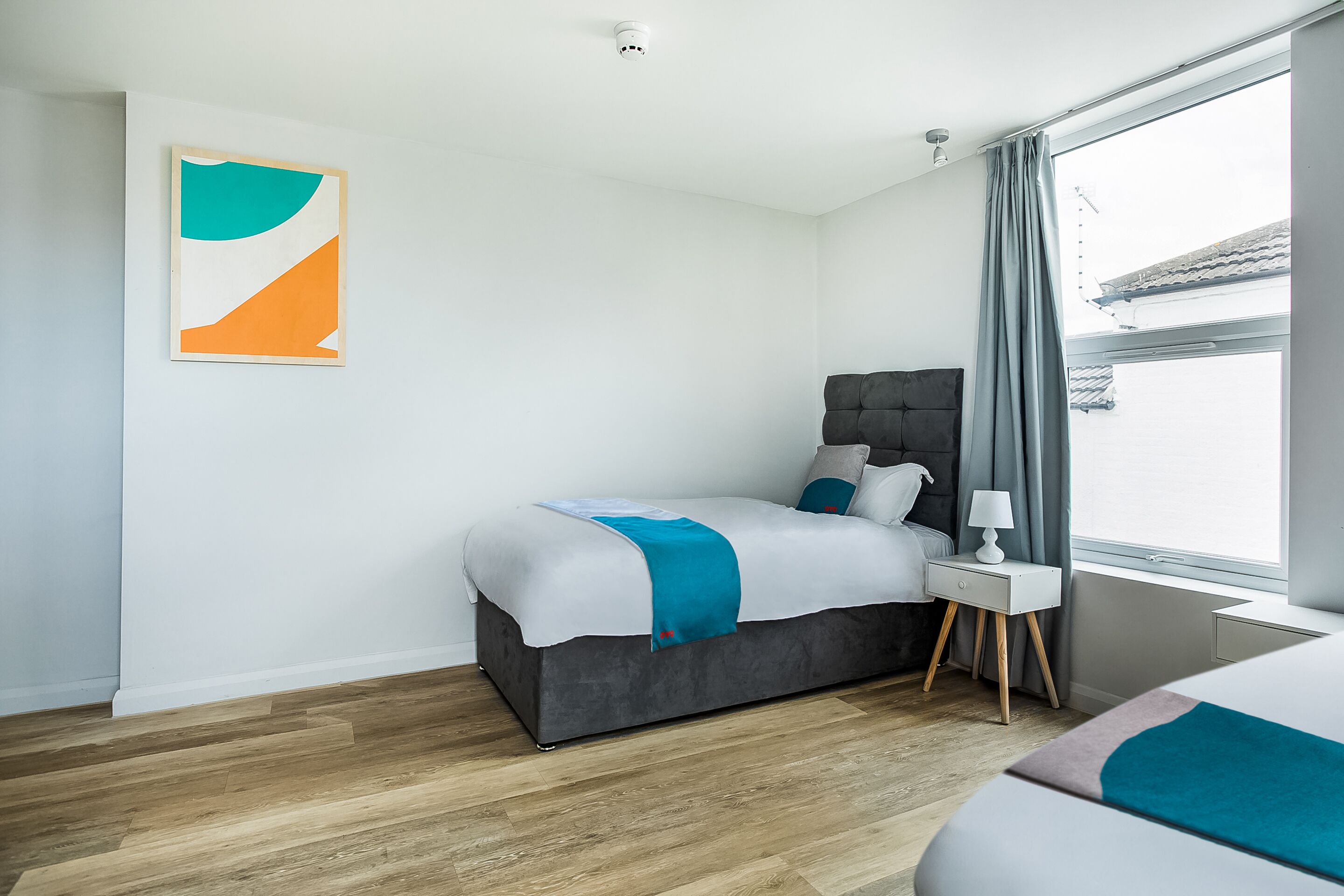 Quarto moderno com cama, mesa de cabeceira e janela com cortinas.