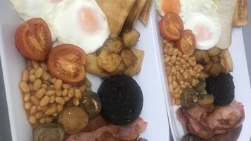 Um prato de café da manhã com ovos, torradas, tomate, feijão, cogumelos e salsichas.