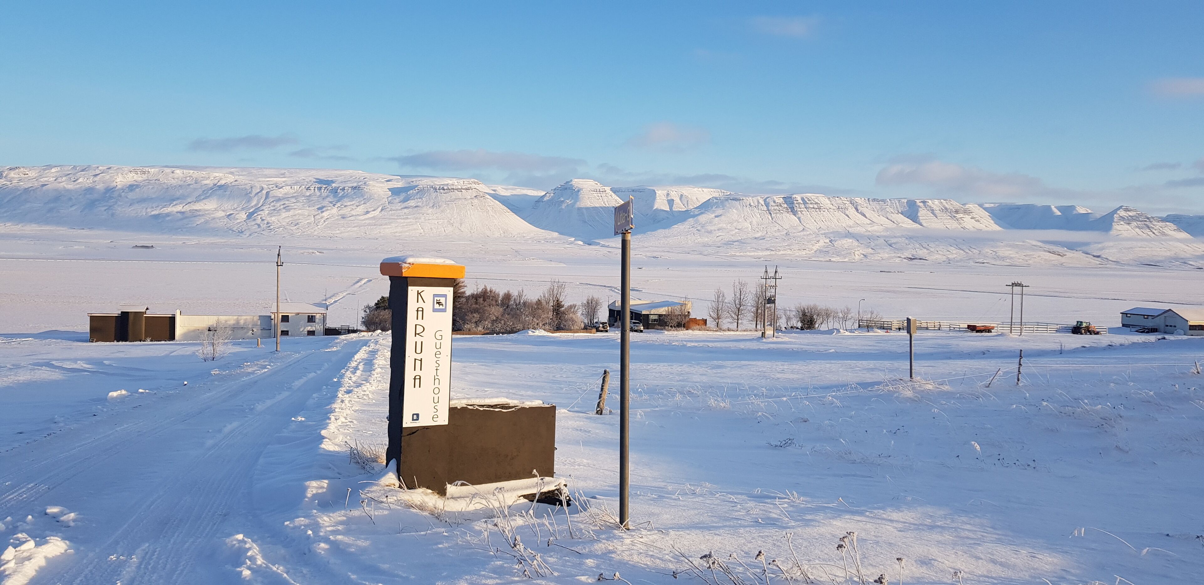 Paisagem coberta de neve com uma placa indicando uma hospedaria.