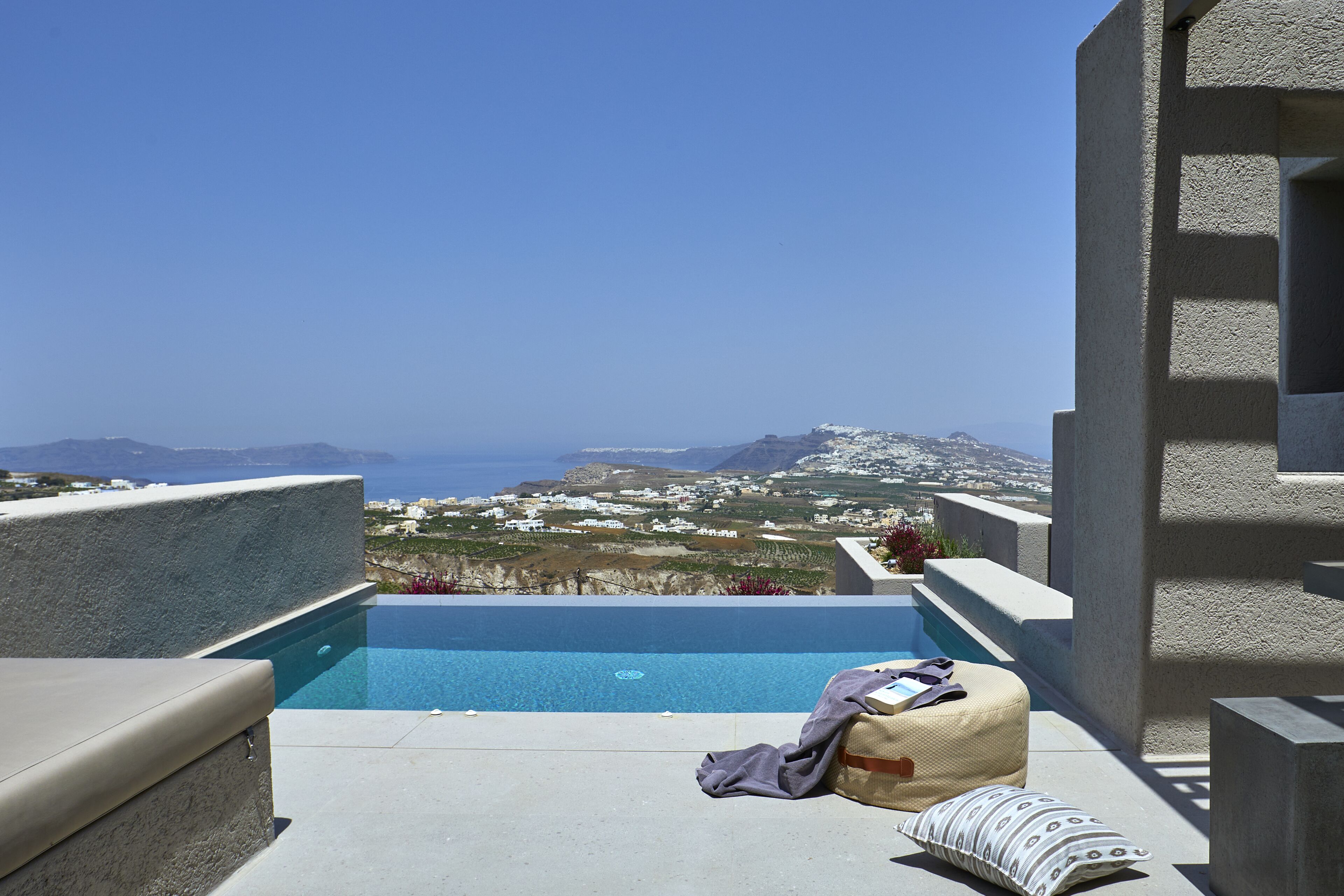 Área de piscina com vista para o mar e paisagem ao longe.
