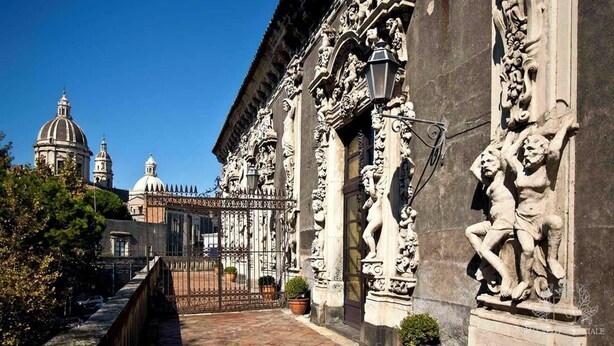 Um edifício histórico com esculturas elaboradas e um portão.