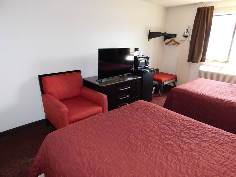 Quarto de hotel com duas camas, televisão, escrivaninha com computador e uma cadeira.