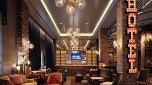 Um lobby de hotel moderno com mobiliário de couro, área de bar e uma grande tela de televisão.